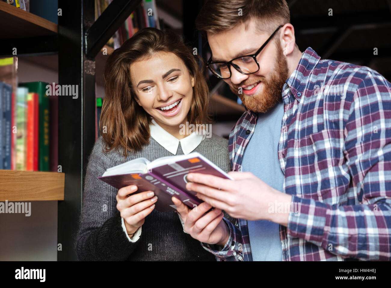 Two happy students working in library with books together Stock Photo ...