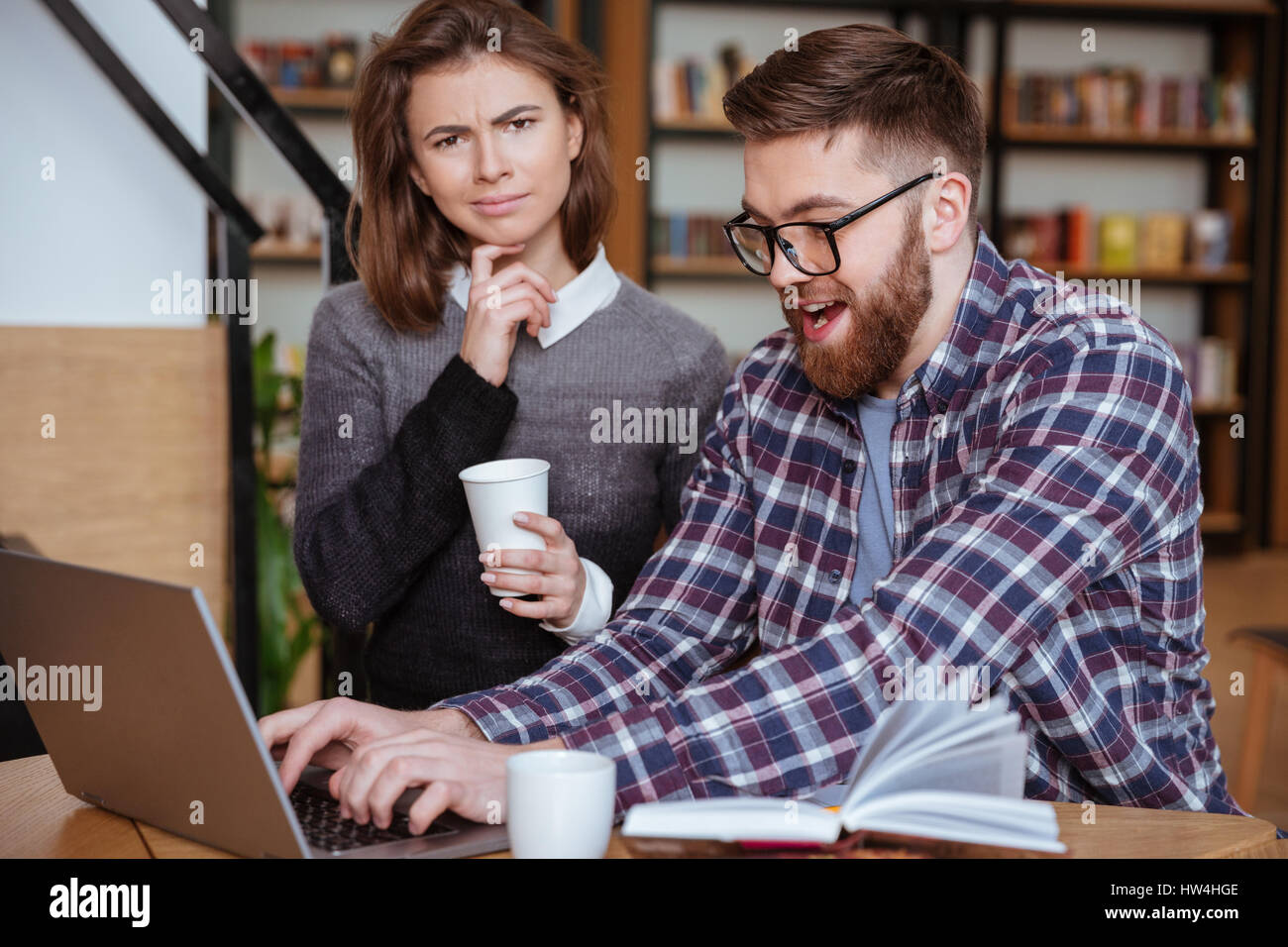 Young students man and woman doing homework with laptop in the library ...