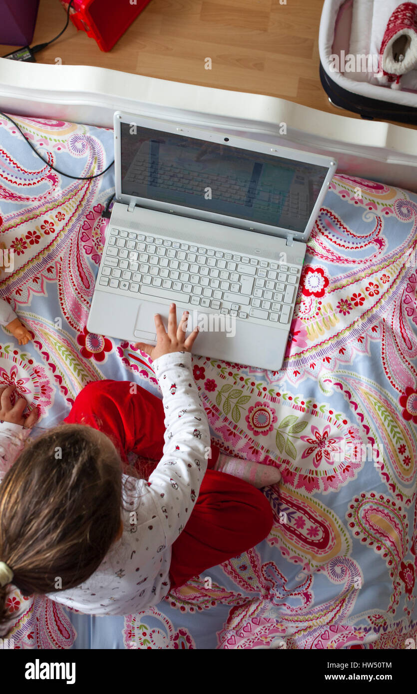 Little girl sitting in bed and playing online games in her bedroom ...