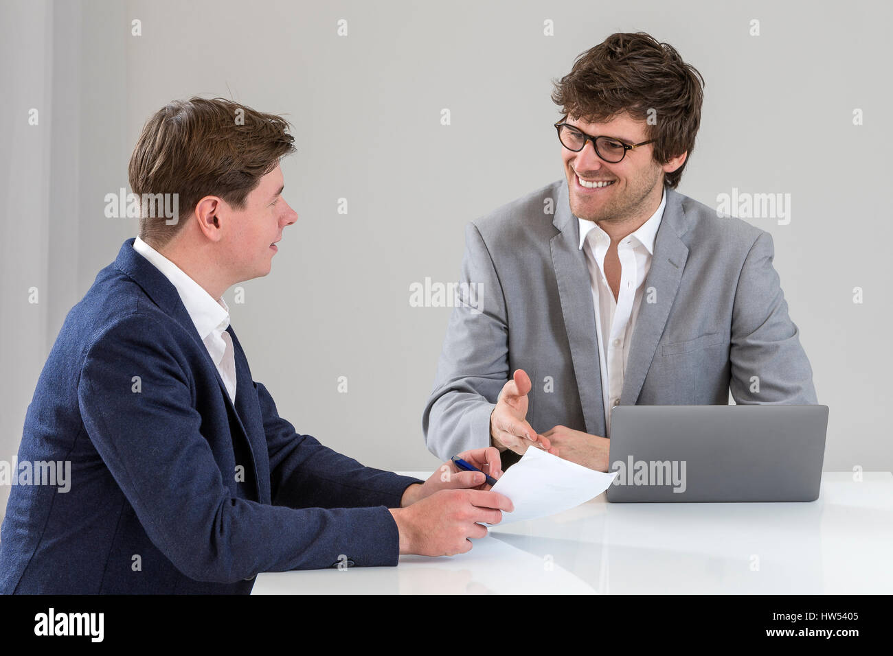 Two young businessmen signing contracts at office desk Stock Photo - Alamy