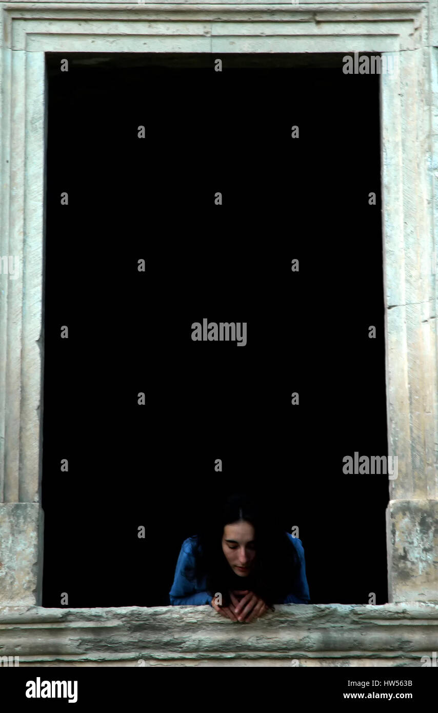 Beautiful girl in the window looking down Stock Photo - Alamy