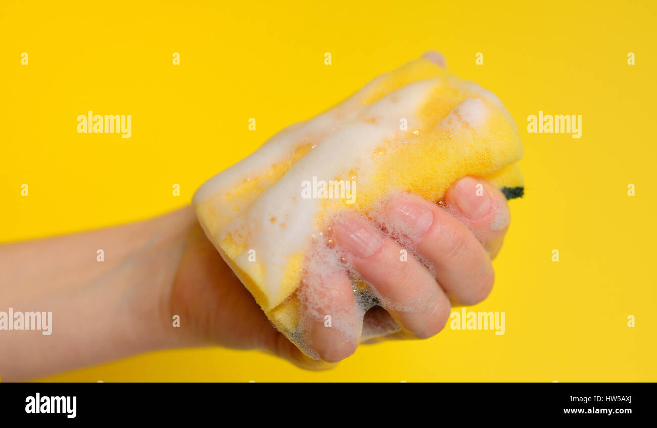Hand with sponge with foam on yellow background Stock Photo - Alamy