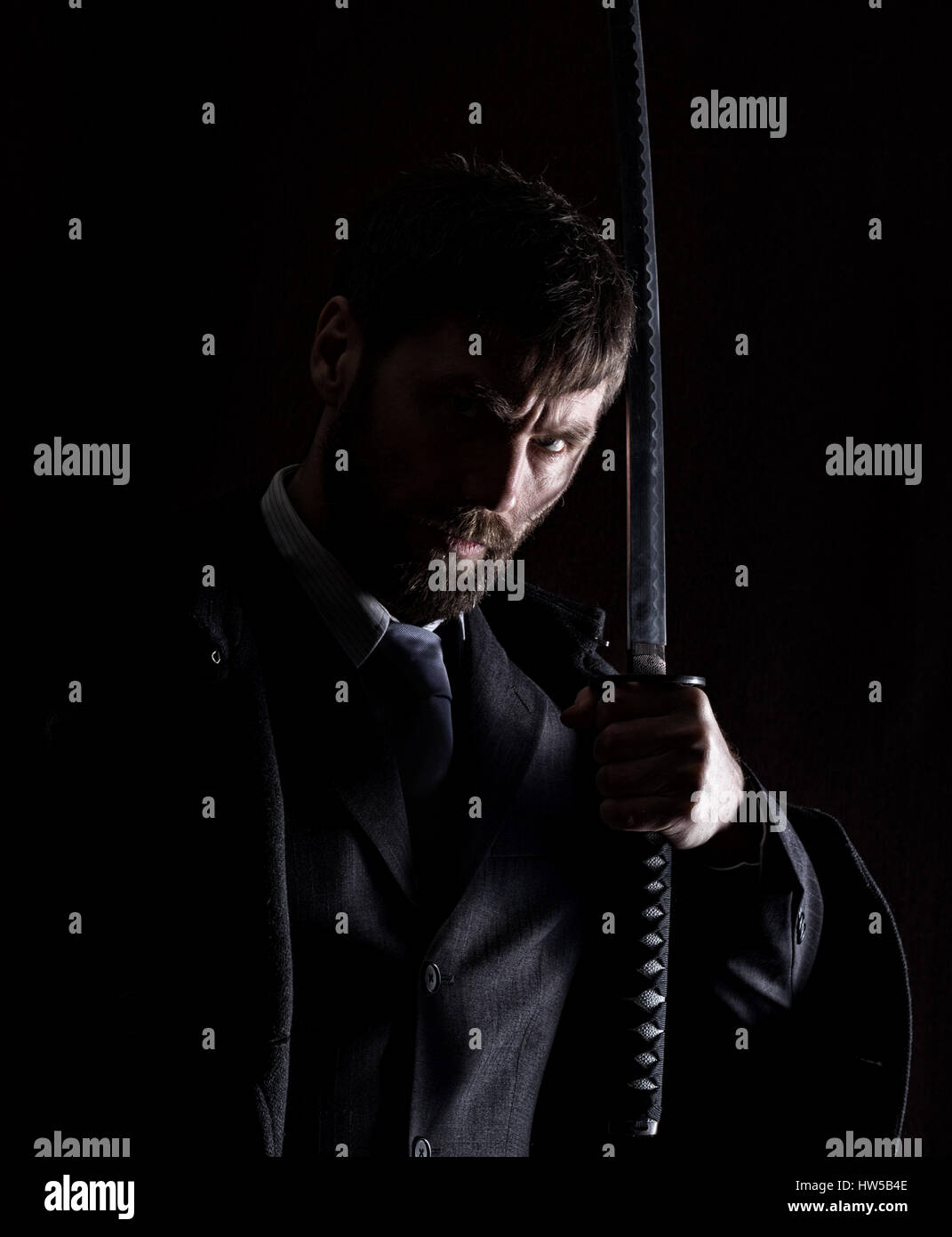 stern angry businessman in a wool coat with sword in dark background ...