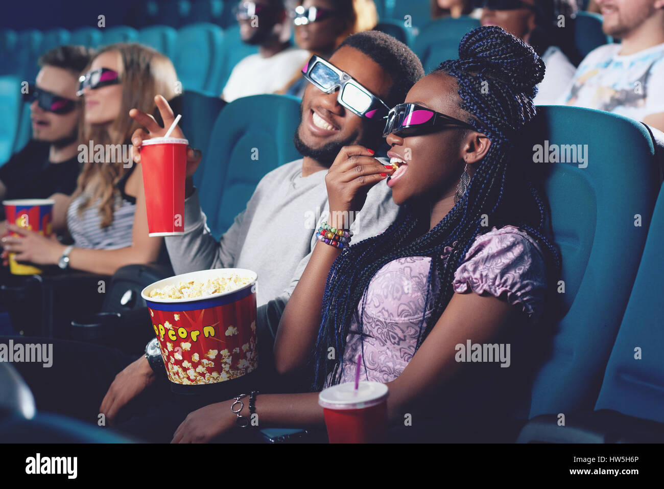 Couple of africans eating popcorn, drinking cola in cinema Stock Photo ...