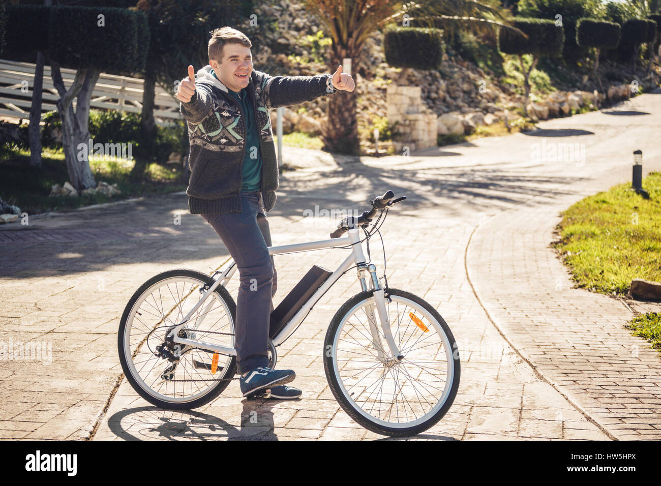 Young man riding bike in park showing thumb up Stock Photo - Alamy