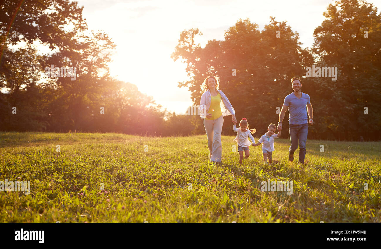 Happy family running together in park Stock Photo - Alamy