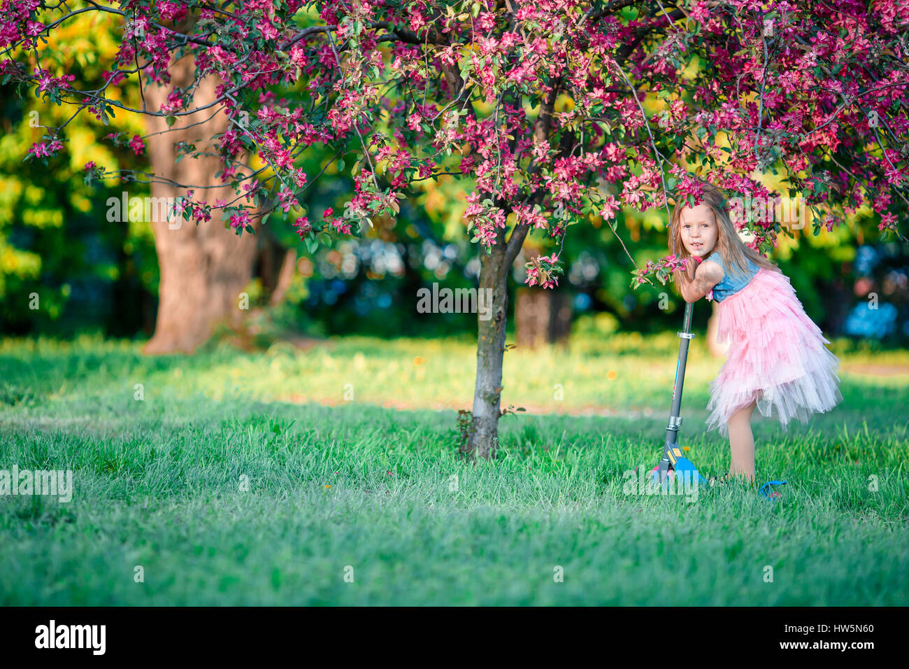 Adorable little girl in blooming apple garden on beautiful spring day ...