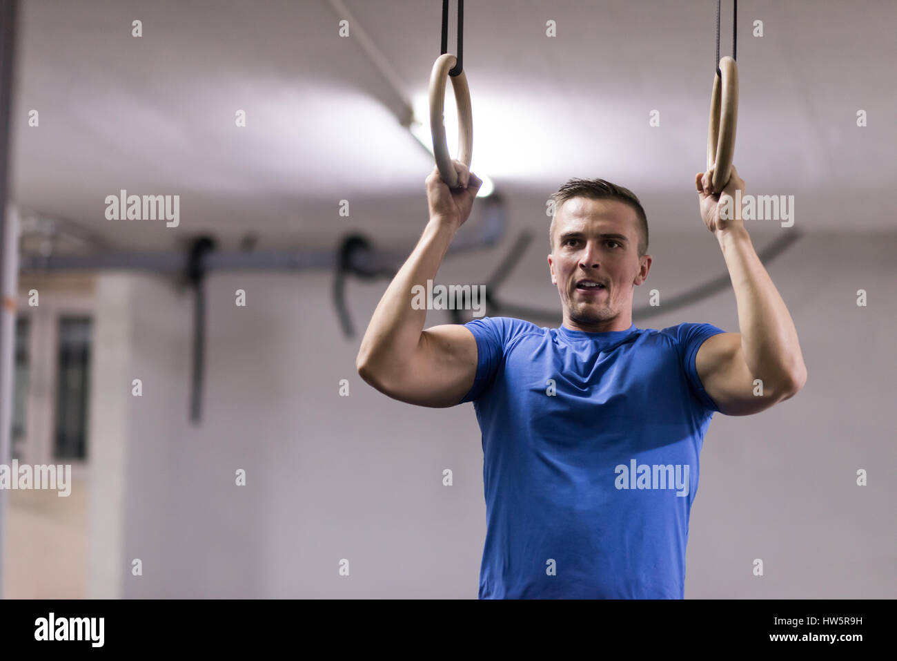 Fitness handsome man doing dipping exercise using rings in the gym ...
