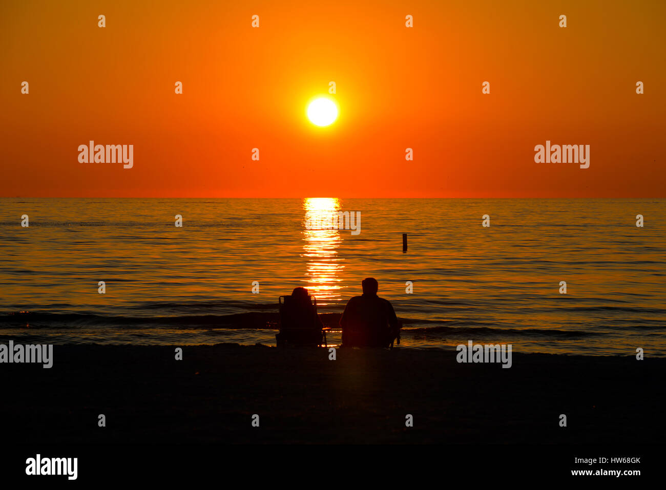 two people watching sunset on beach Stock Photo - Alamy