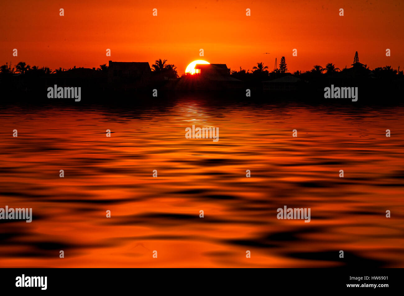 large ball sun setting into an island Stock Photo - Alamy