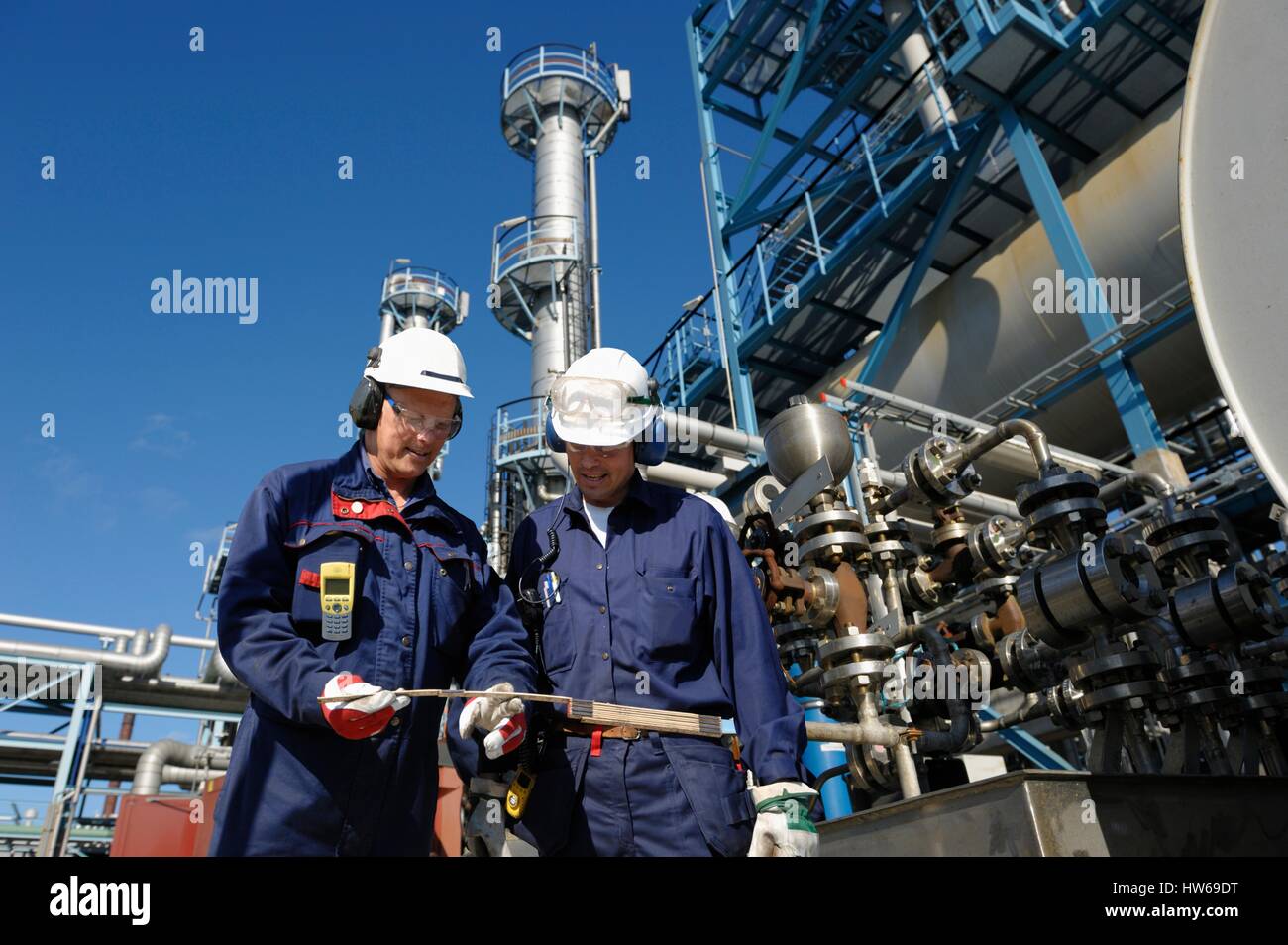 MODEL RELEASED. Oil refinery workers and pipework Stock Photo - Alamy