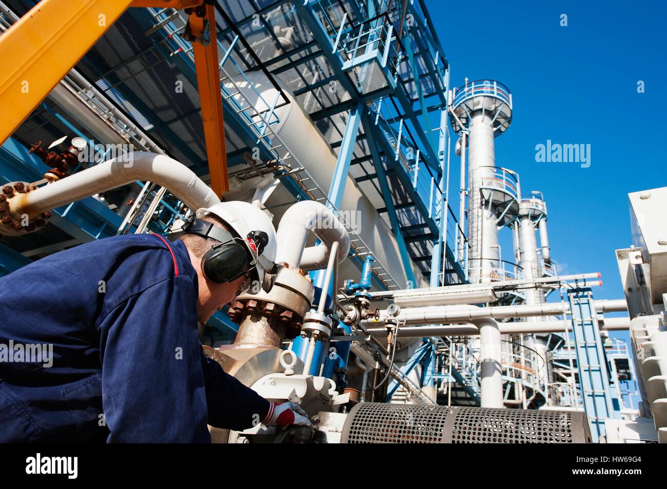 MODEL RELEASED. Worker checking pipework on an oil and gas refinery ...