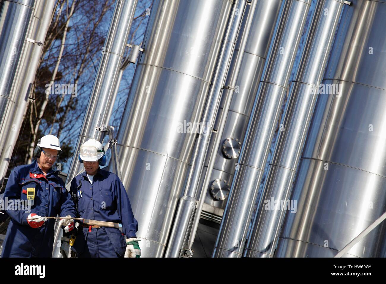 MODEL RELEASED. Oil refinery workers and pipework Stock Photo - Alamy