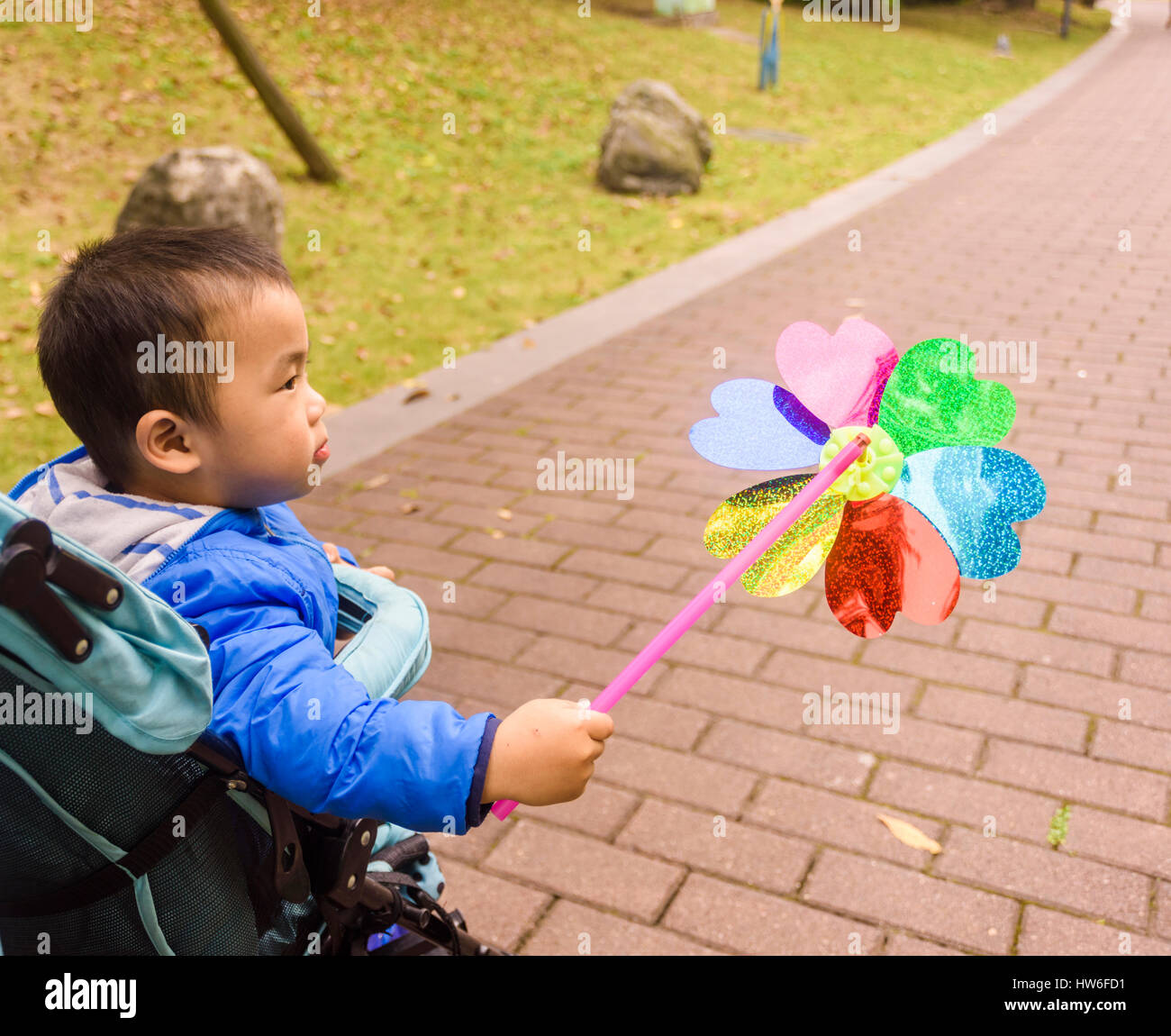 Toddler boy playing pinwheel while riding in stroller Stock Photo - Alamy