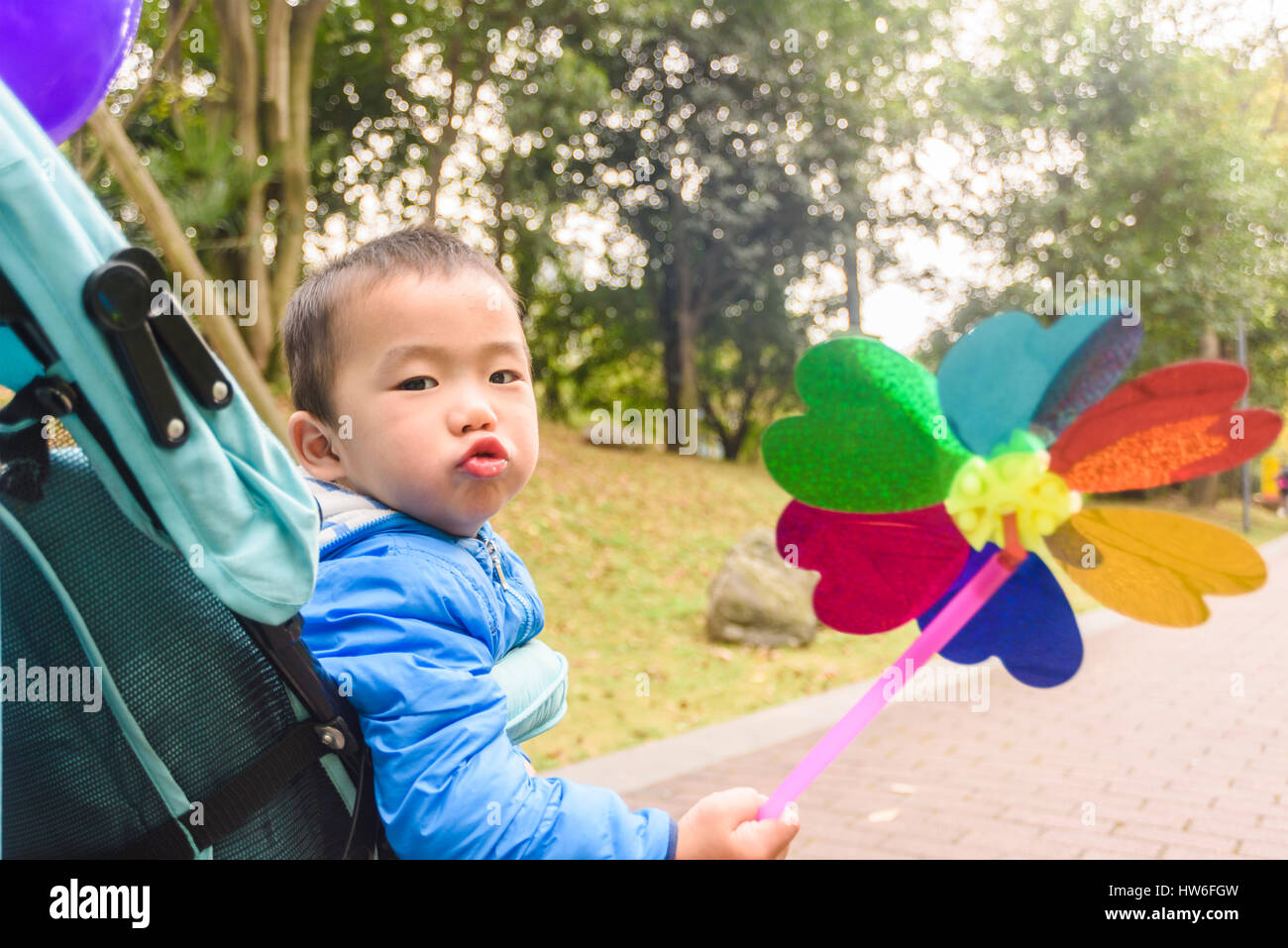 Toddler boy playing pinwheel while riding in stroller Stock Photo - Alamy