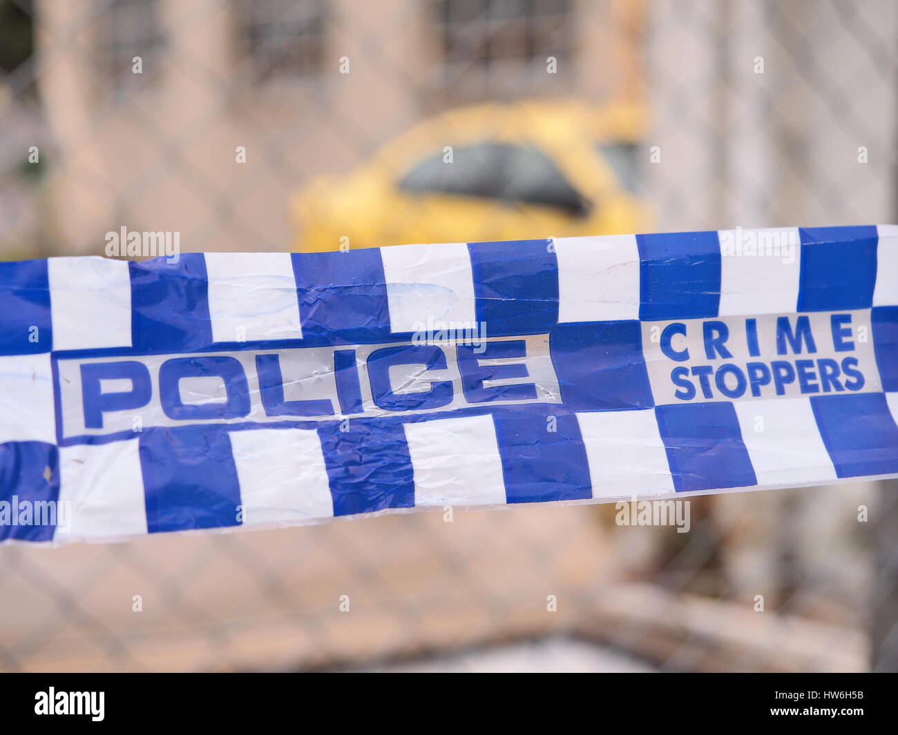 Blue and white Police tape cordoning off a area with a yellow car at a ...