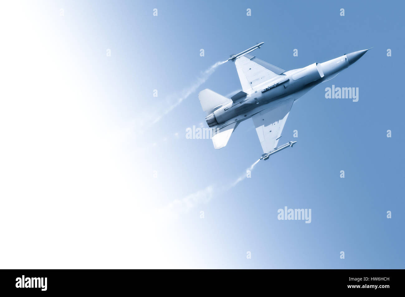 military jet making an aerobatic roll through a gradient blue sky Stock ...