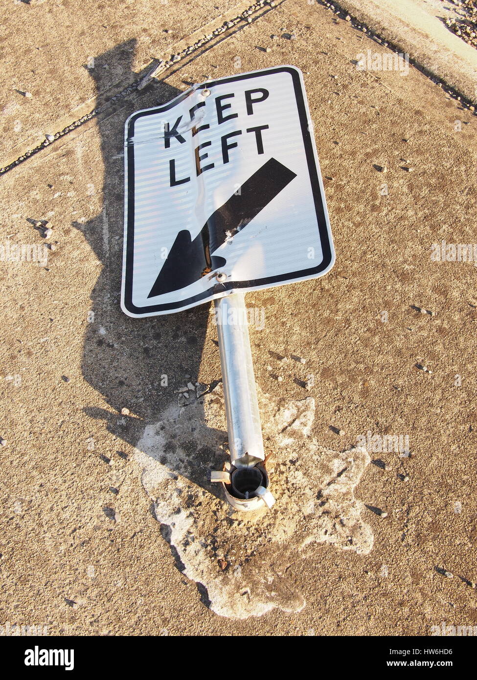 Broken road sign at a traffic island, bent to the ground after heavy ...