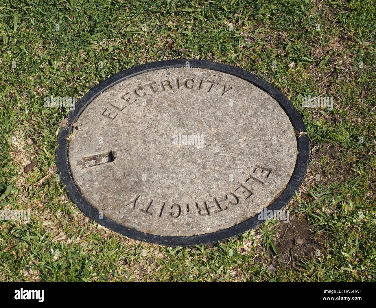 Round concrete lid on a electrical pit on a nature strip marked with ...