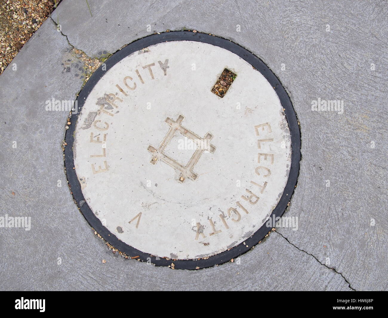Round concrete lid on a electrical pit on a foot path marked with ...