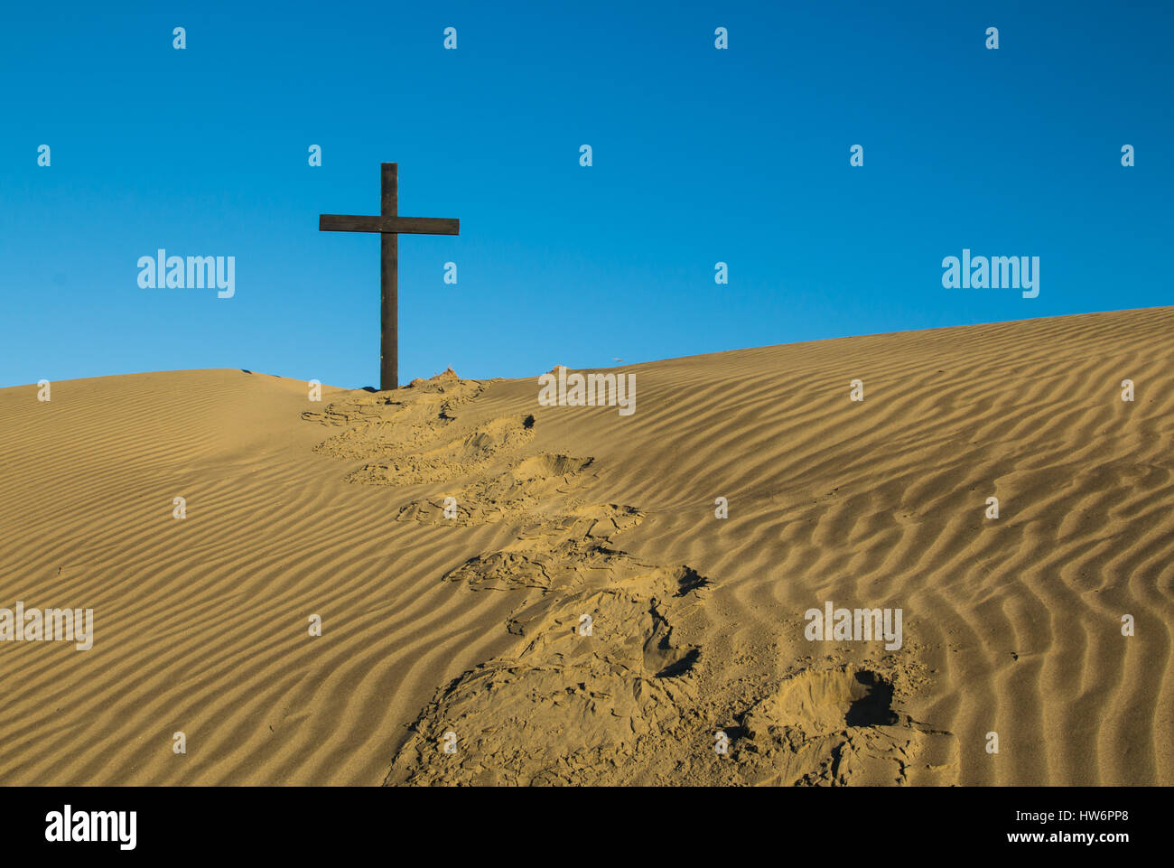 Foot prints in the sand leading up to a cross Stock Photo - Alamy