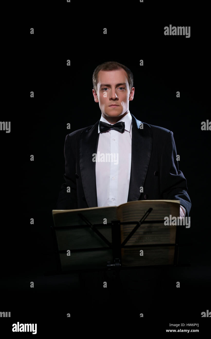 Orchestra conductor in black tuxedo in dark studio Stock Photo - Alamy