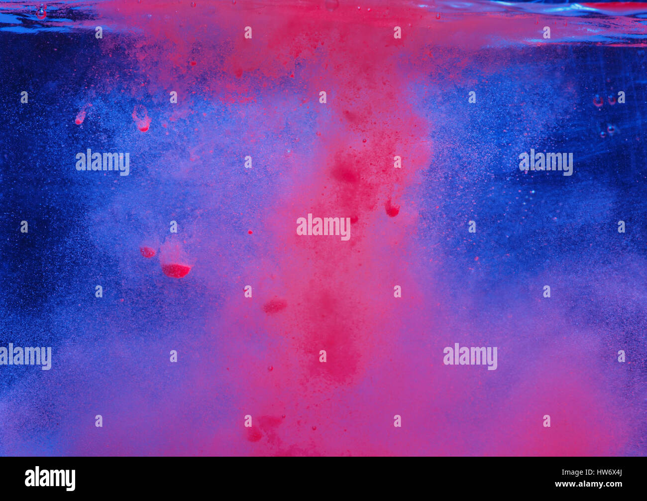 Abstract image of a pink powder falling into a blue liquid Stock Photo ...