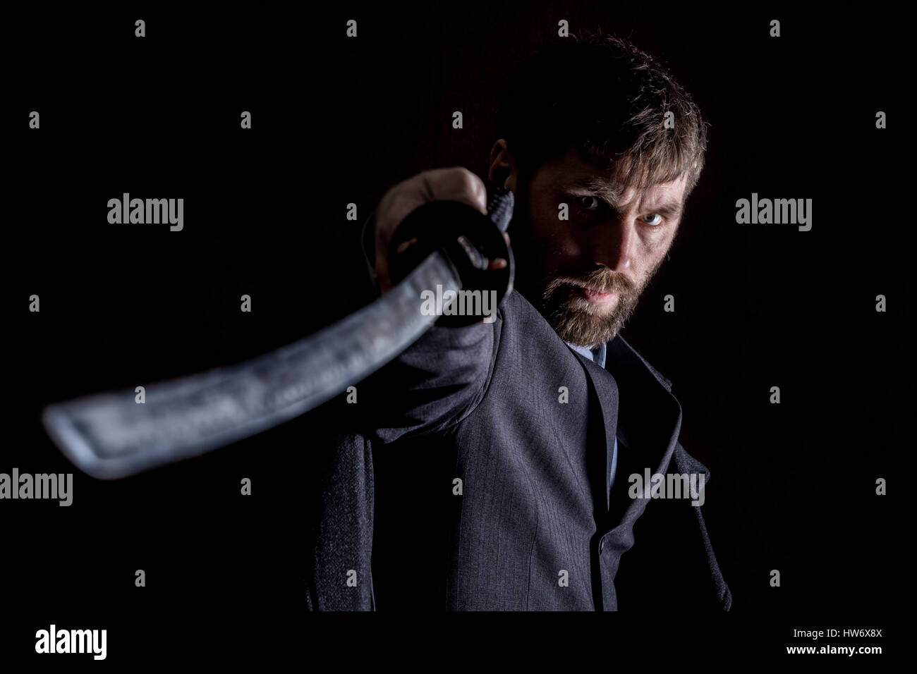 stern angry businessman in a wool coat with sword in dark background ...