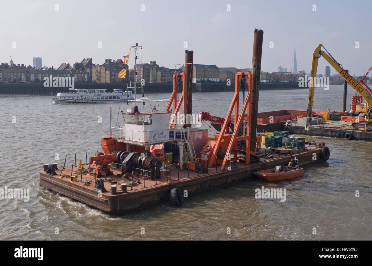 Maintenance dredging boat and cranes on river Thames by new office ...