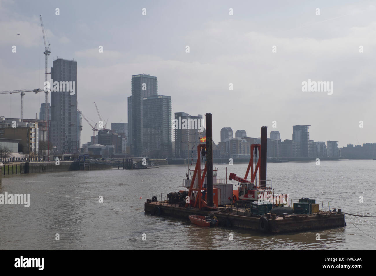 Maintenance dredging boat and cranes on river Thames by new office ...