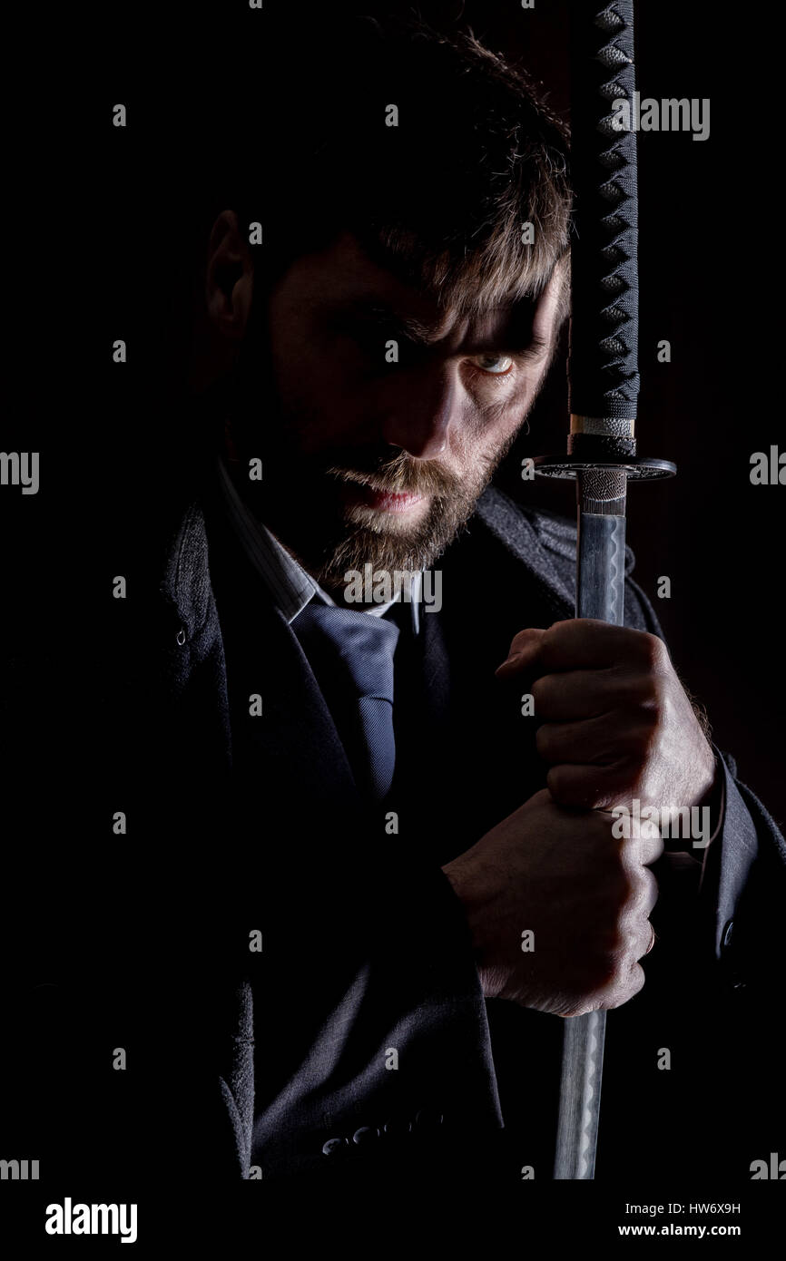 stern angry businessman in a wool coat with sword in dark background ...