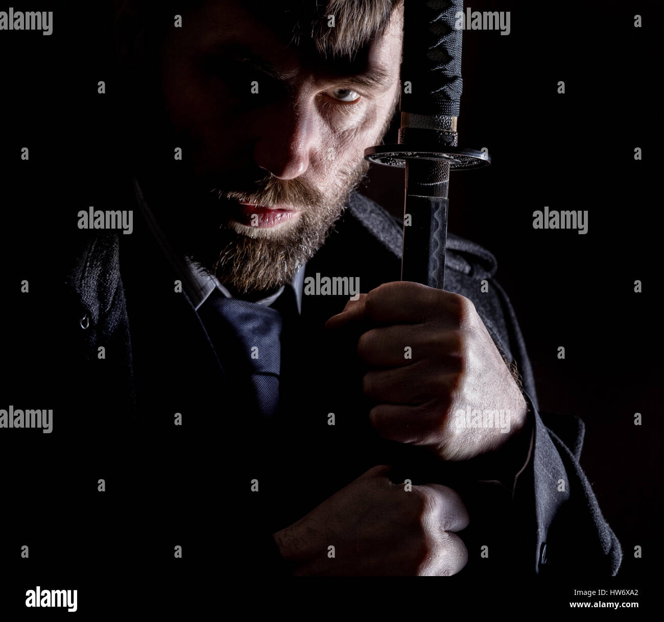 stern angry businessman in a wool coat with sword in dark background ...