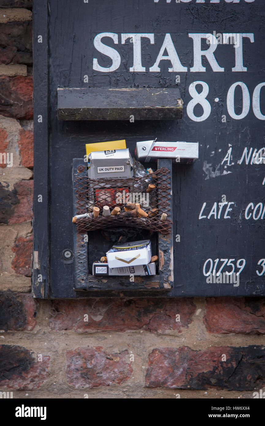 Close-up of used cigarette butts and empty packets discarded in a wire ...