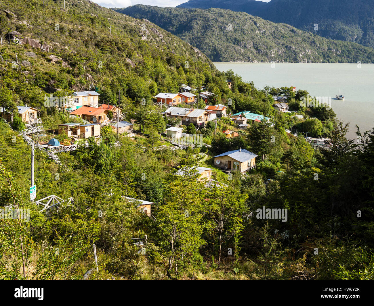 Houses and wooden boardwalk on the hillside of Caleta Tortel, sea in ...