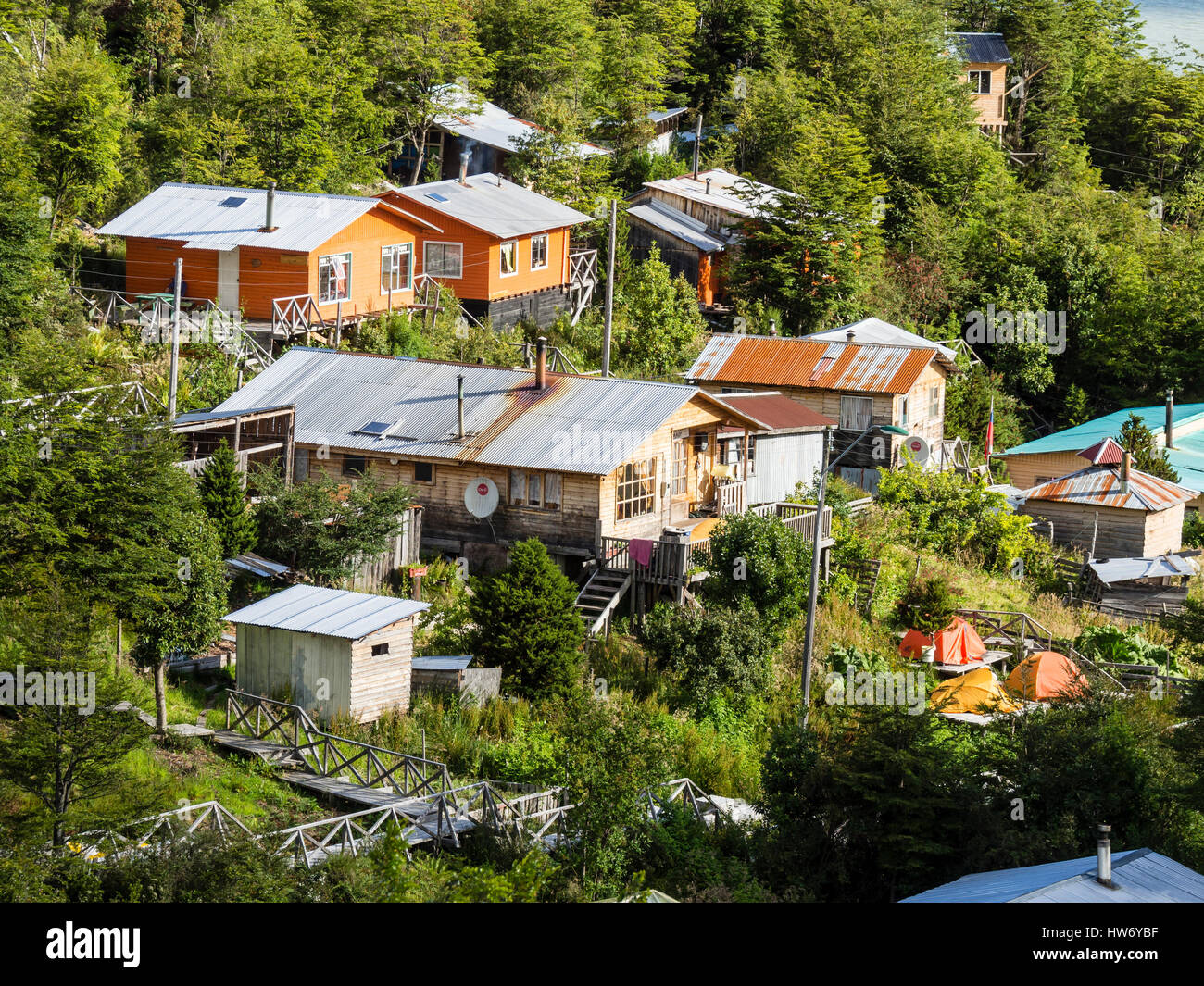 Houses and wooden boardwalk on the hillside of Caleta Tortel, sea in ...