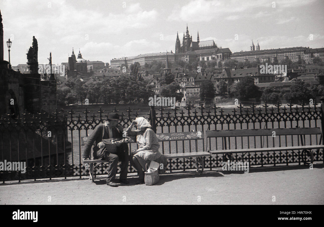 1938, historical, couple sit together on a bench overlooking the Vitava ...