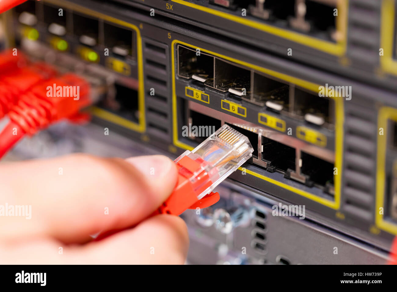 IT consultant connects a network cable into switch in datacenter Stock ...