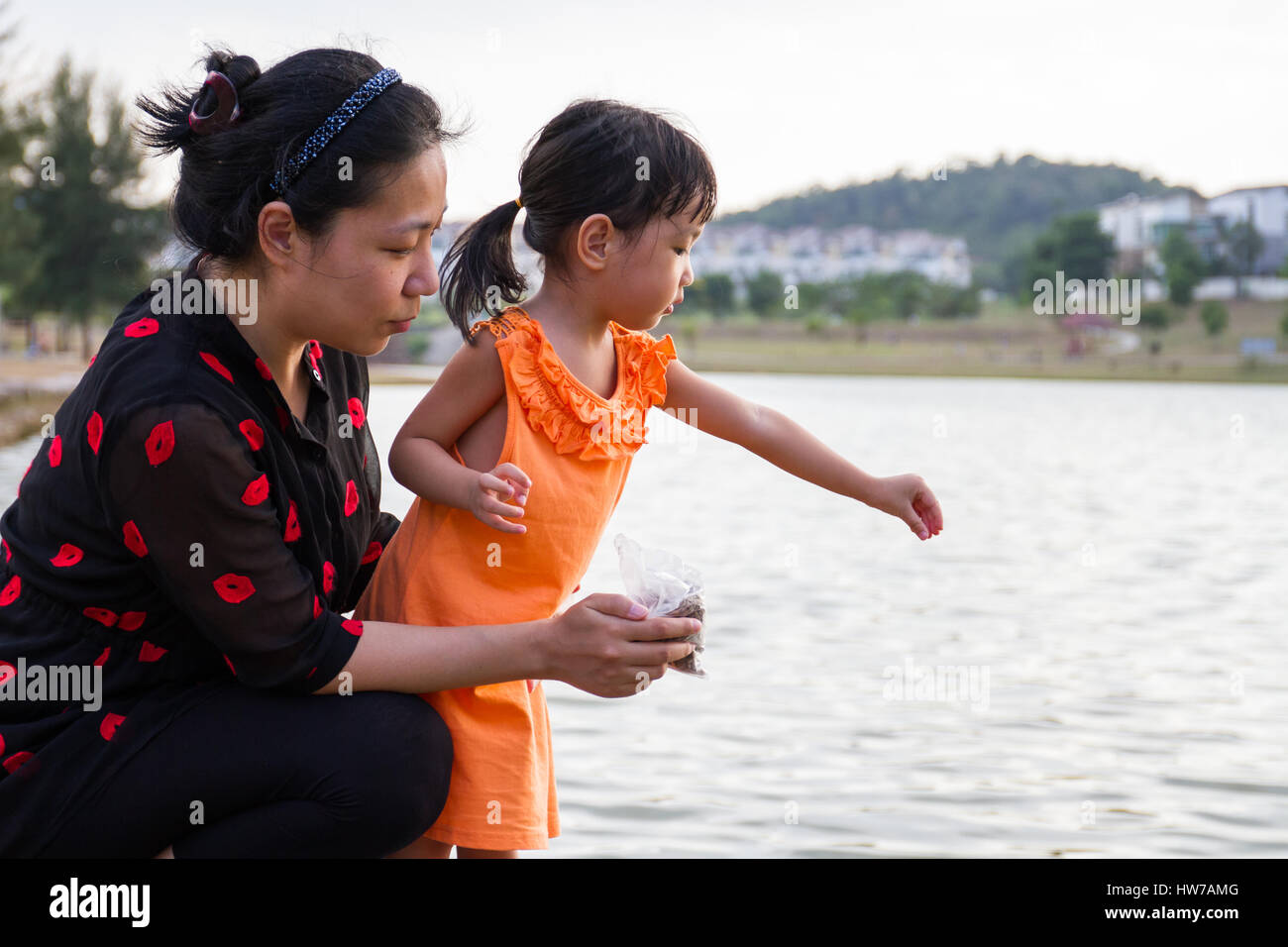 Asian Mother and Daughter Feeding Fish in the Park Stock Photo - Alamy