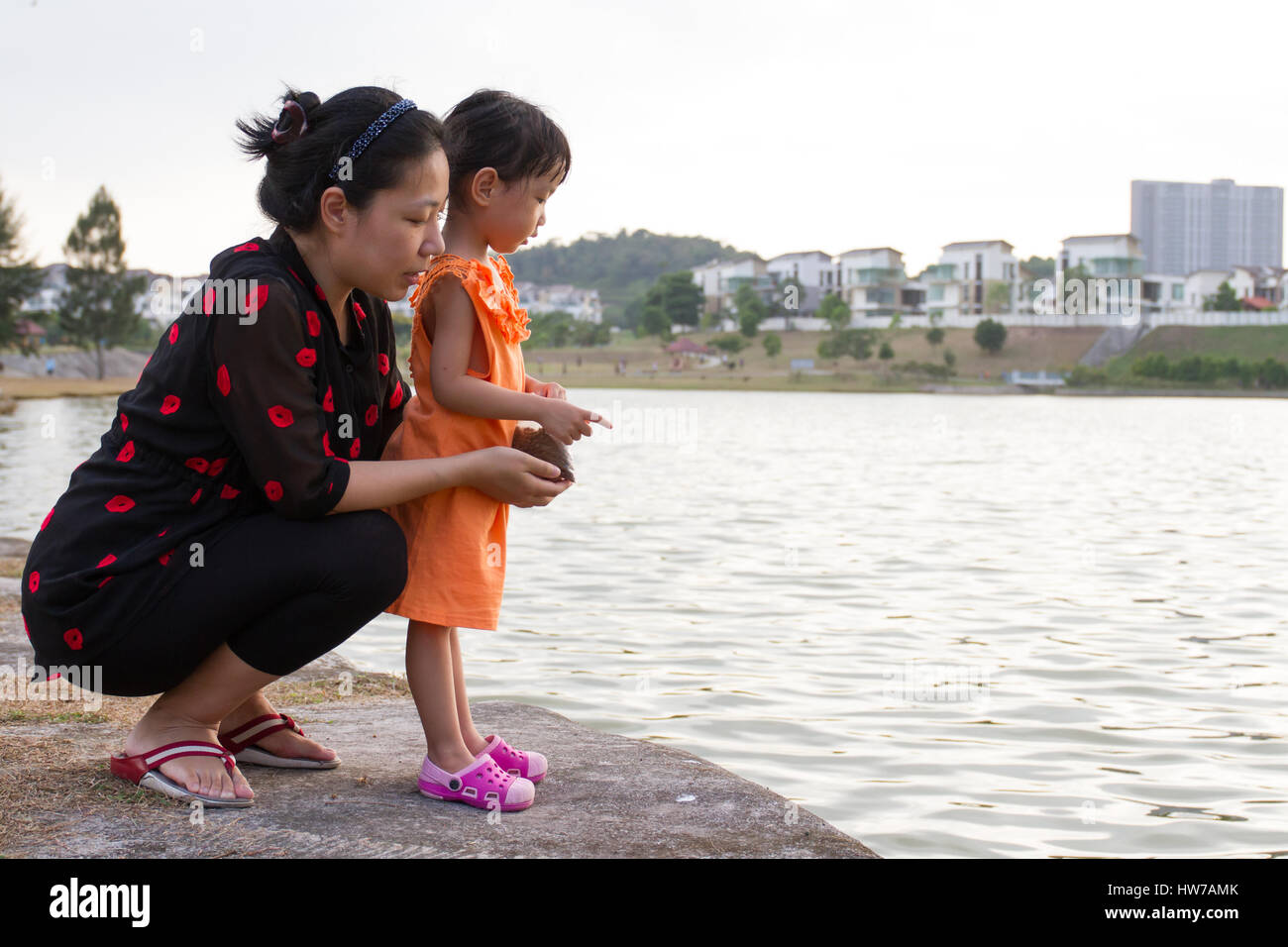 Asian Mother and Daughter Feeding Fish in the Park Stock Photo - Alamy