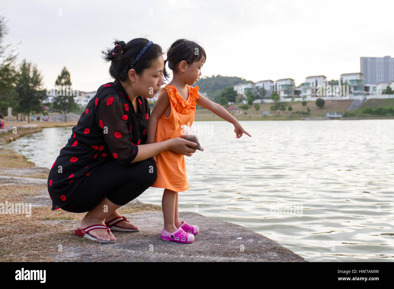 Asian Mother and Daughter Feeding Fish in the Park Stock Photo - Alamy