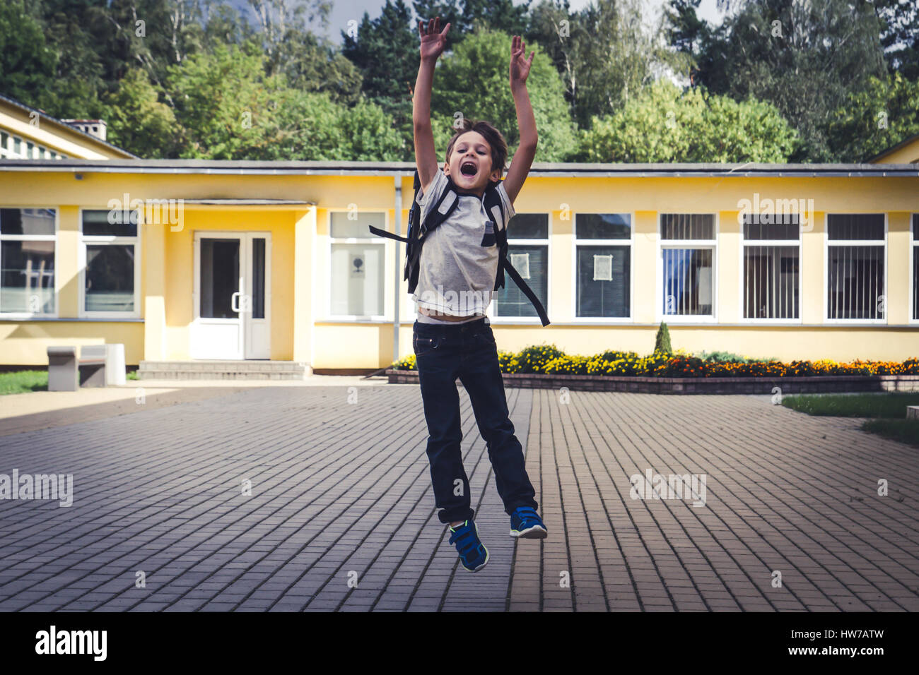 Happy kid with backpack jumping and having fun in front of school ...