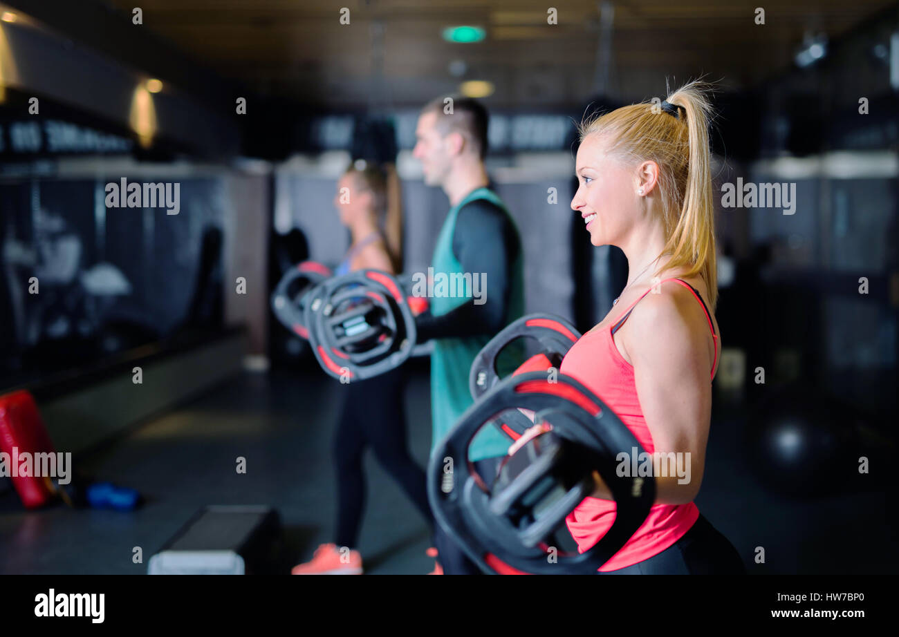 Three beautiful young fitness people working out with weights together ...