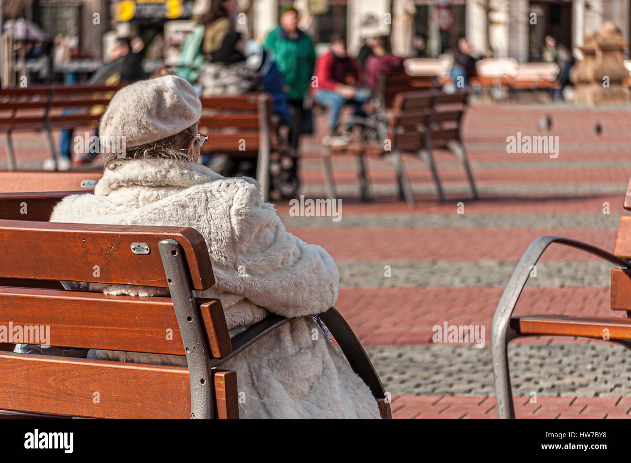 Elderly woman resting on a bench in a plaza. Real people Stock Photo ...