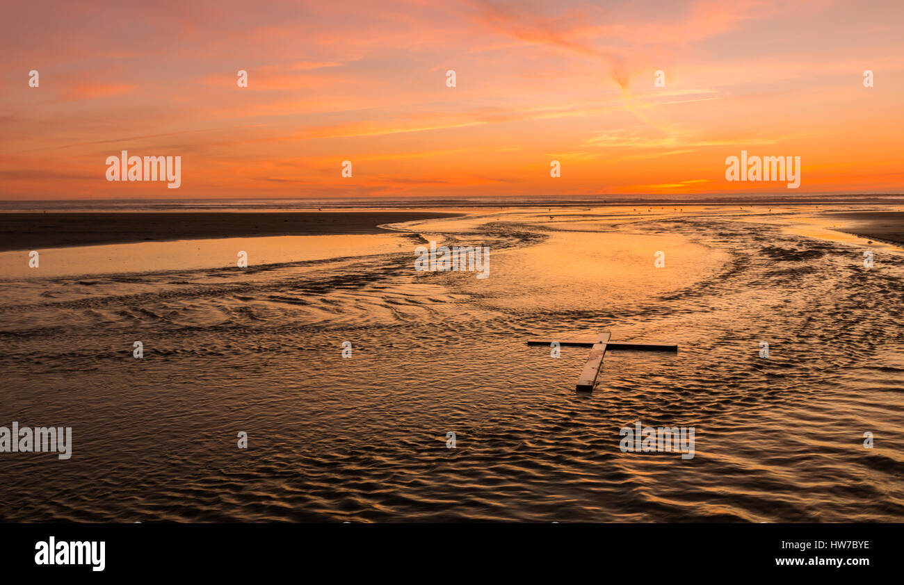 Cross with a flowing stream water around it, at a beach with the sunset ...