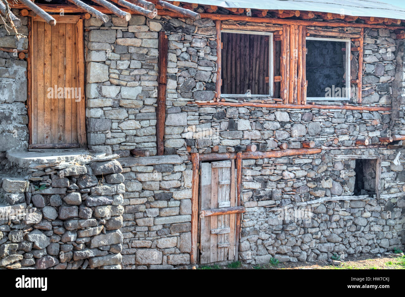 Unfinished stone house with wooden door and windows closeup Stock Photo ...