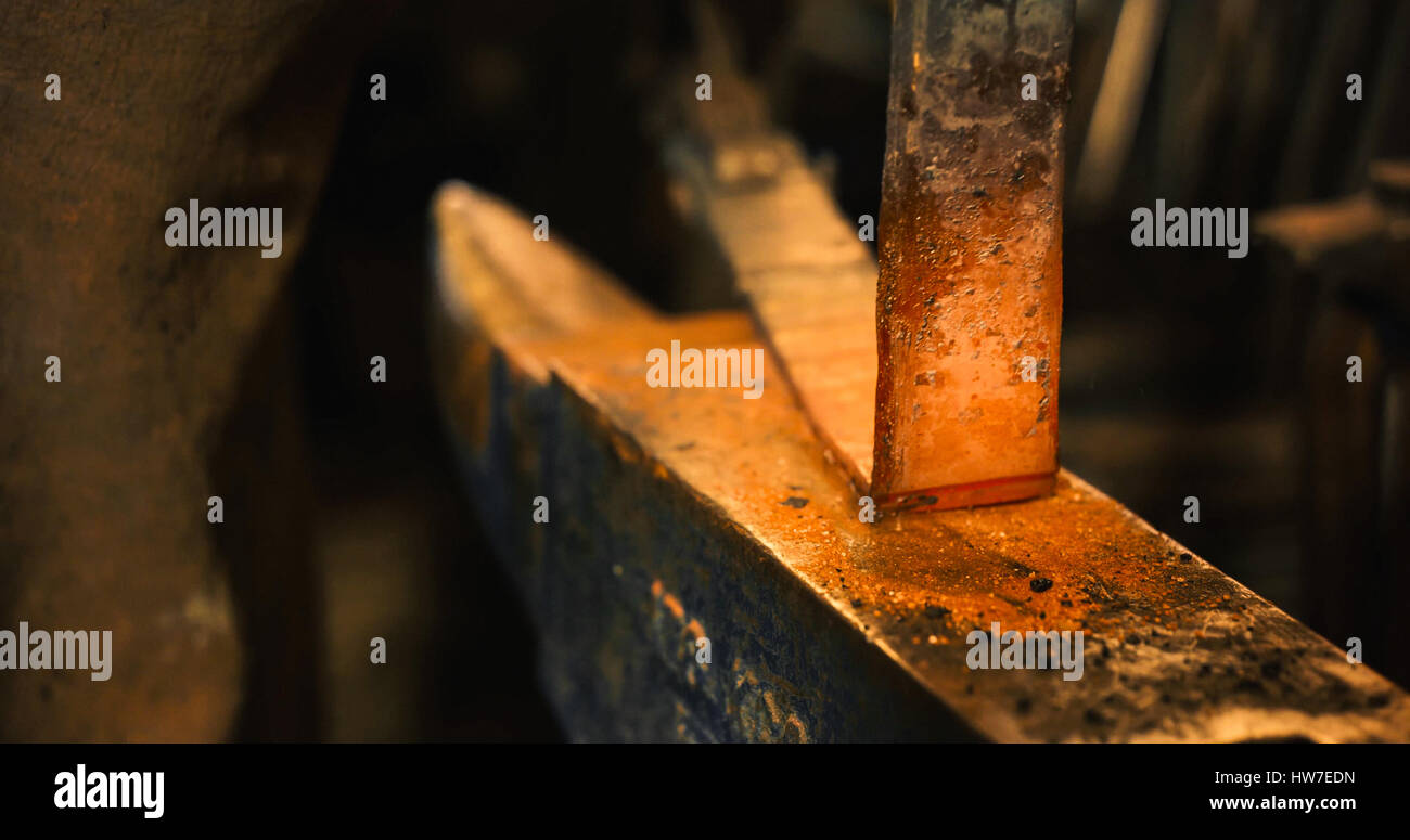 Rod hot iron on the anvil ready to be beaten Stock Photo - Alamy