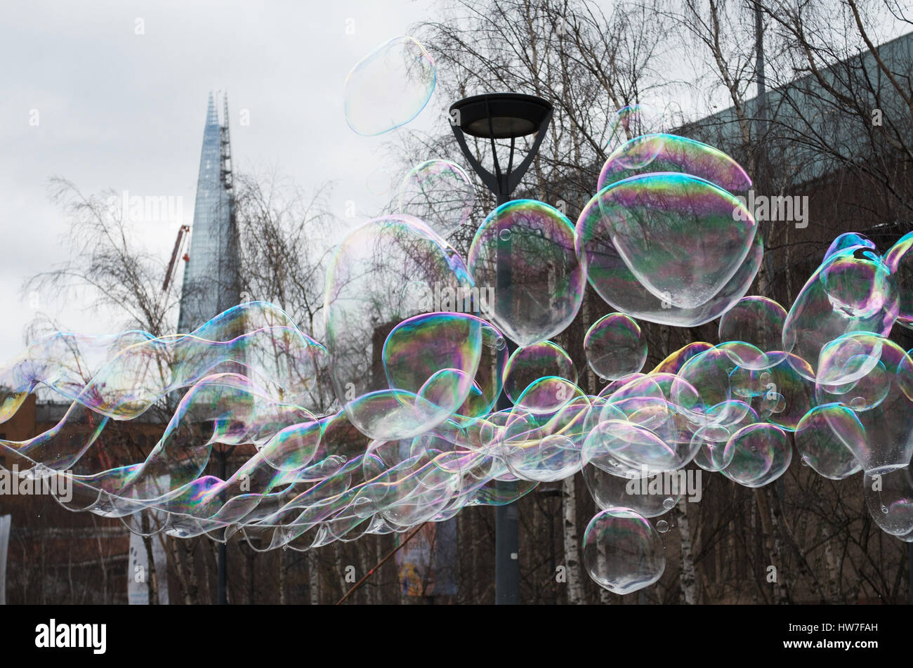 A street entertainer blows giant bubbles along the Thames River in ...
