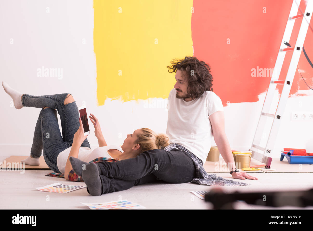 Happy young couple relaxing after painting a room in their new house on ...