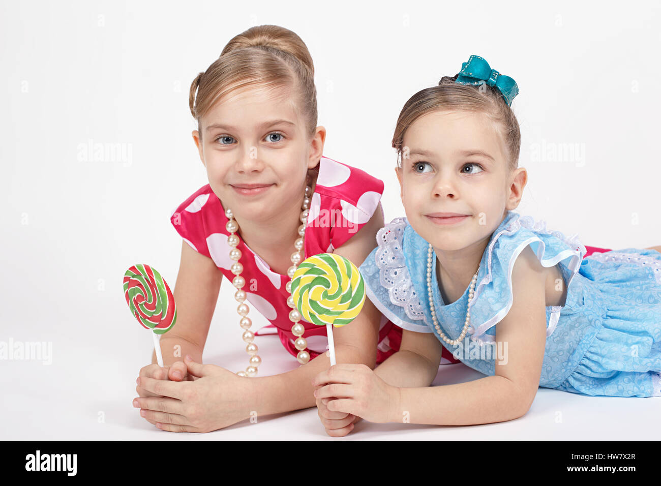 Two sisters lie nearby and hold in his hand a beautiful large candy ...