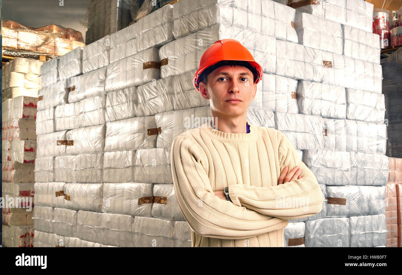 Workman in red helmet inside goods storehouse Stock Photo - Alamy